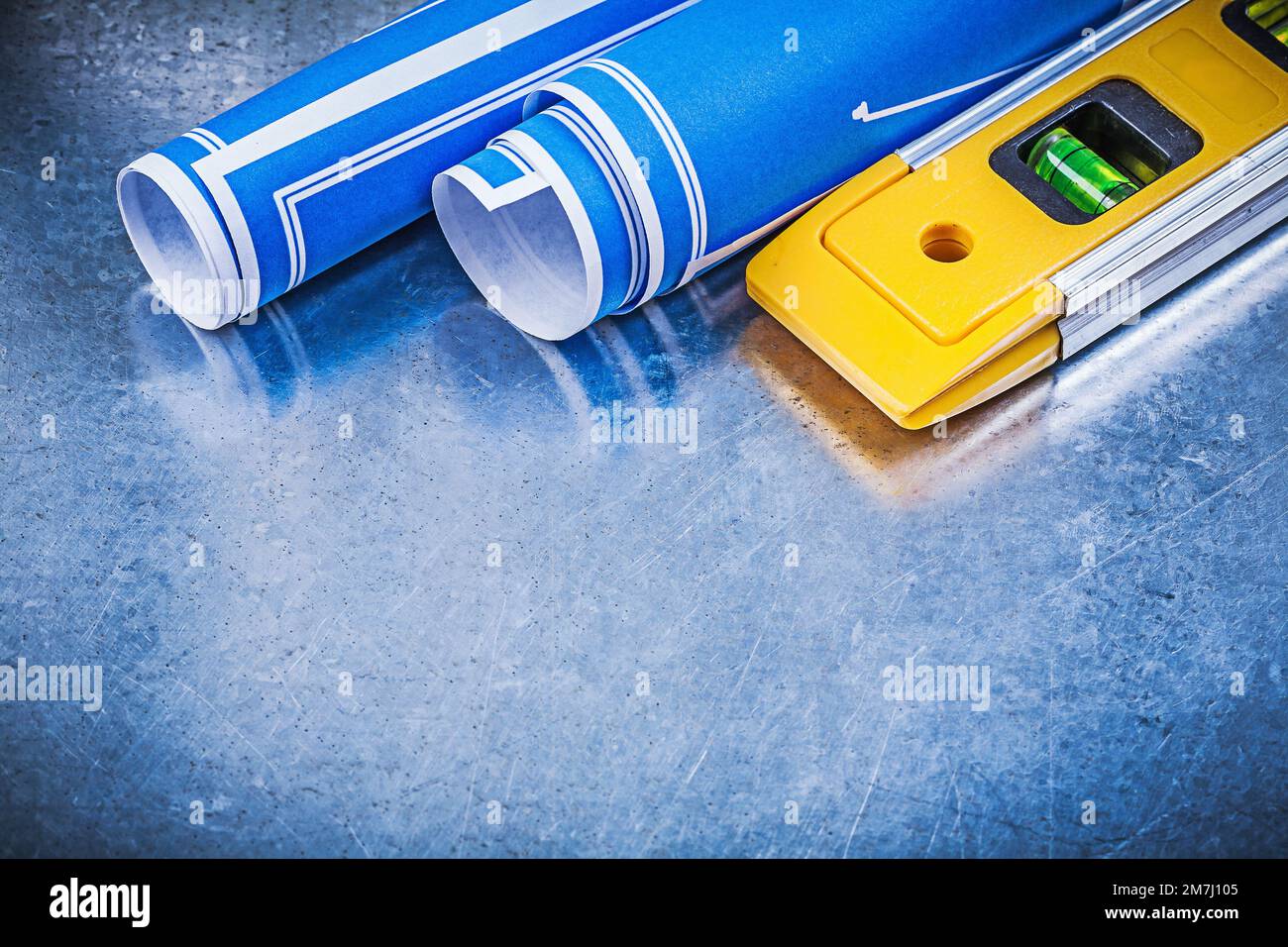 Rolled up construction plans level on metallic background Stock Photo ...