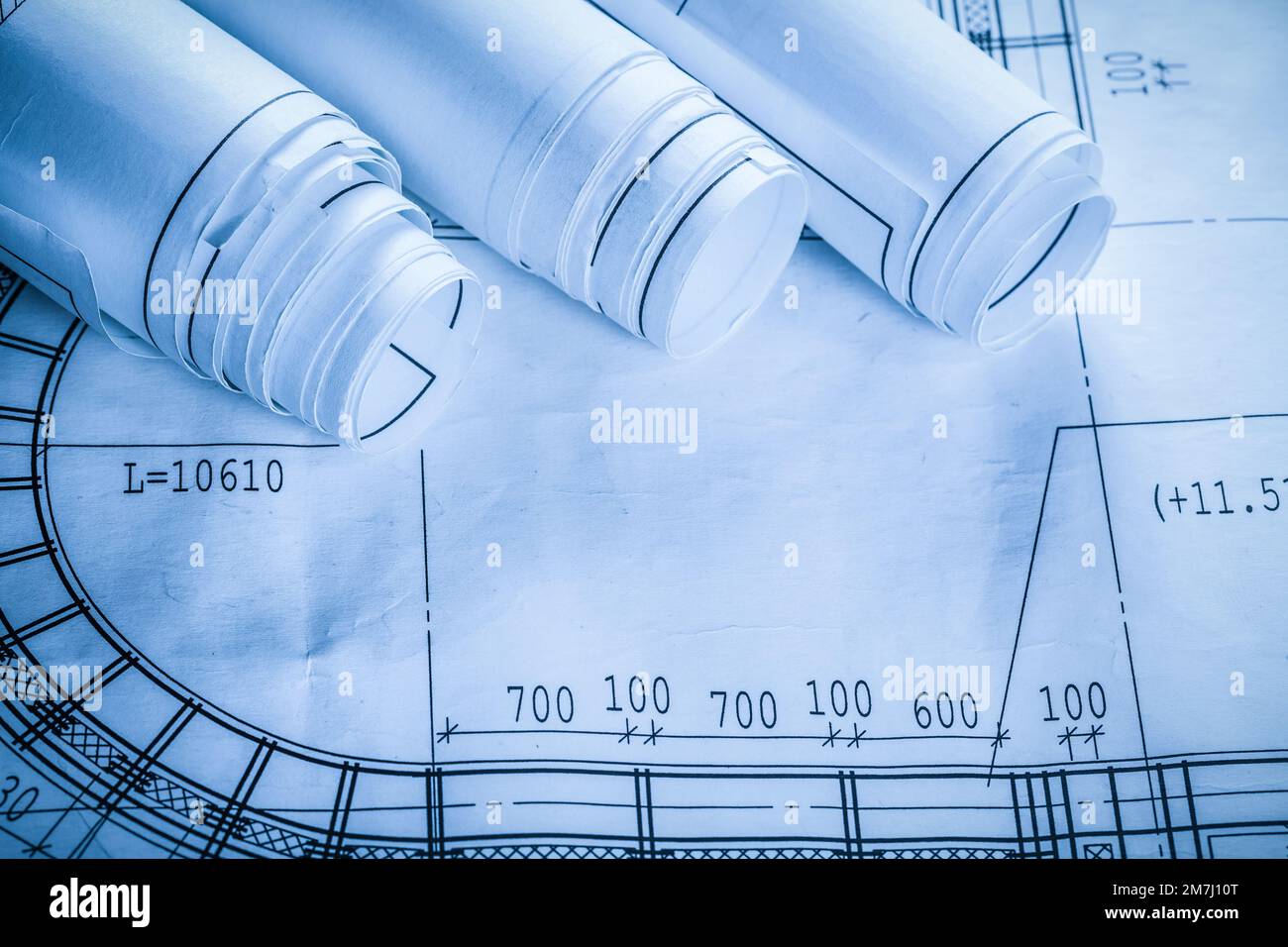 Rolled up white construction drawings on blueprint top view Stock Photo ...