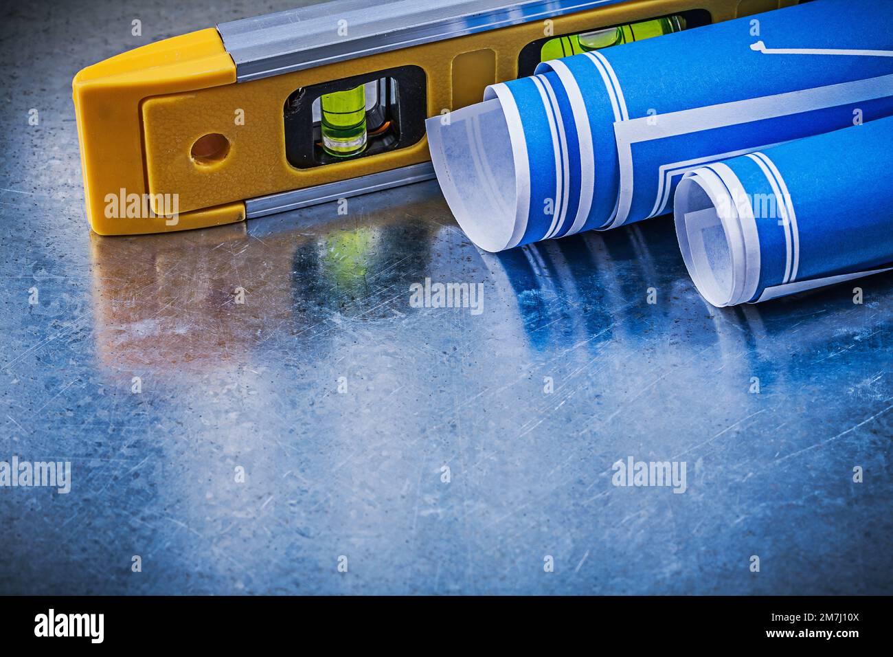 Rolled up engineering drawings construction level on scratched metallic ...