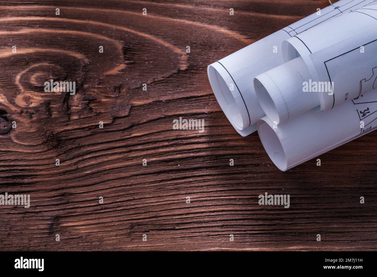Rolls of blueprints on vintage brown wooden board construction concept ...