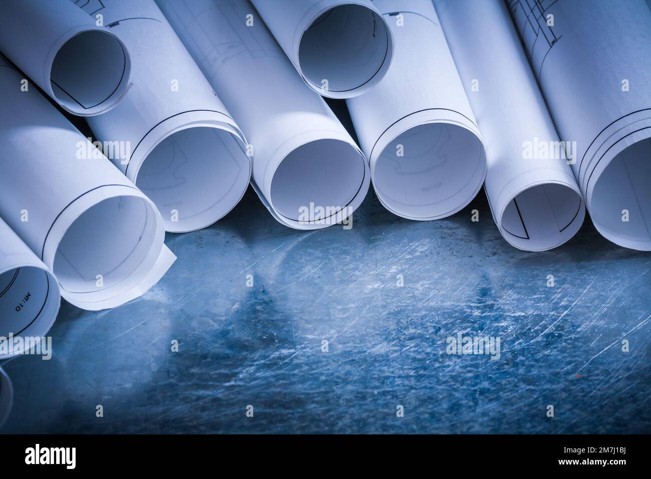 Set Of Rolled Up White Construction Drawings On Scratched Silver Metal Surface Building And