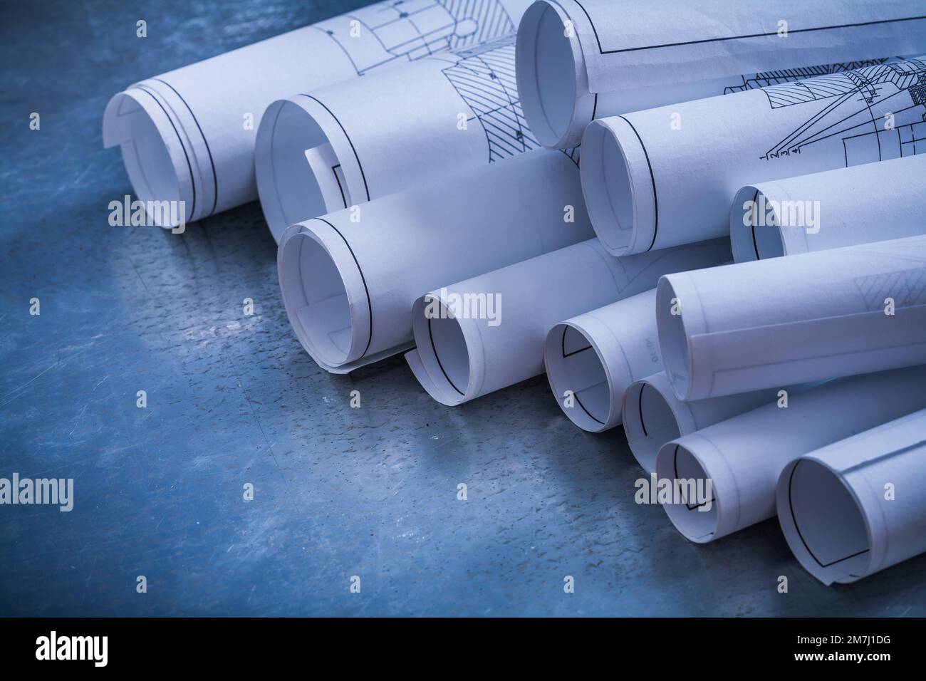 Silver-metal surface with variety of rolled construction plans close-up ...