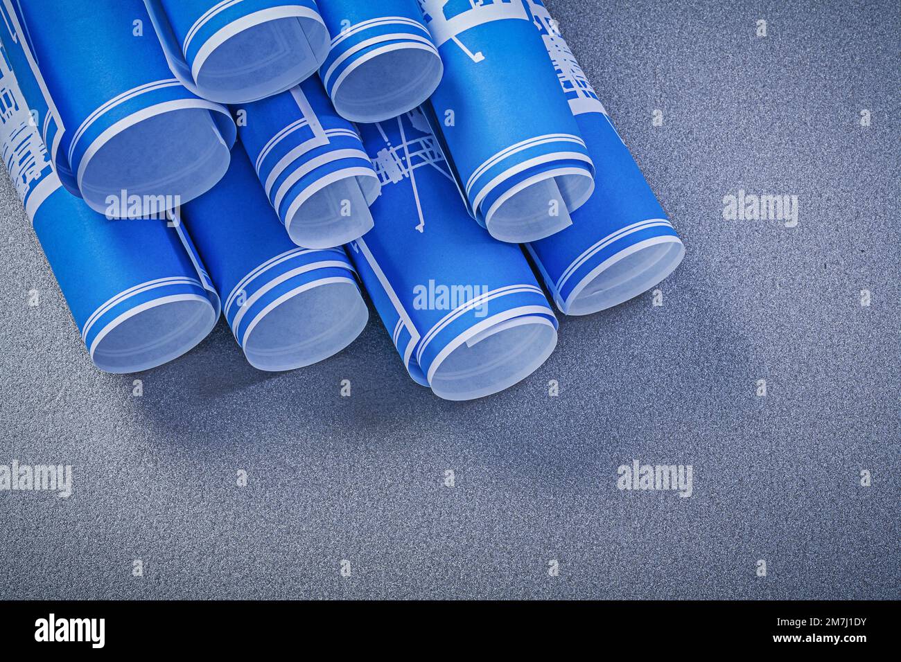 Stack of blue rolled up construction plans on grey background ...