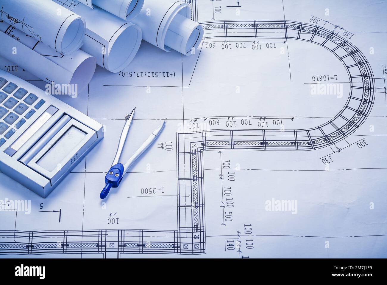 stack of rolled blueprints calculator compass construction concept ...
