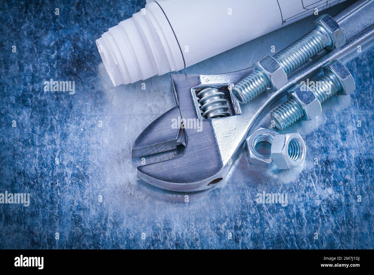 Steel adjustable spanner screw-nuts bolts and blueprints on scratched ...