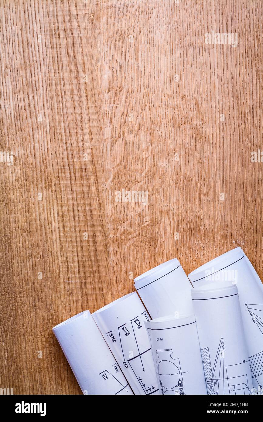 stack of white construction rolled up blueprints on wooden boards with ...