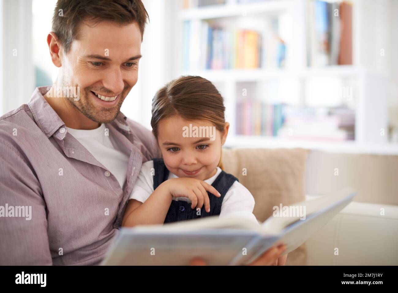 Reading her favourite story. a young father reading a book with his ...