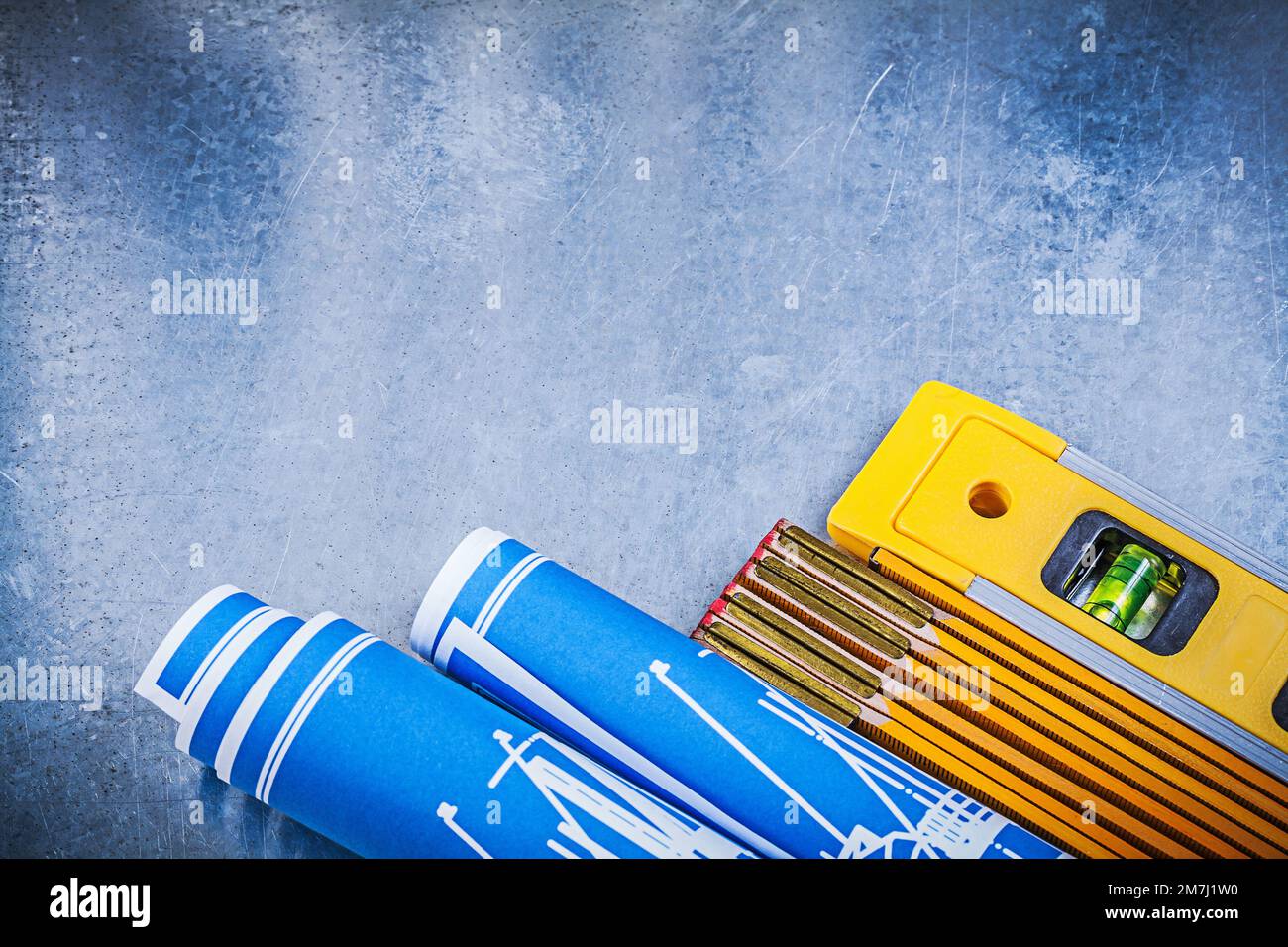 Wooden meter blue rolled construction drawings level on metallic ...