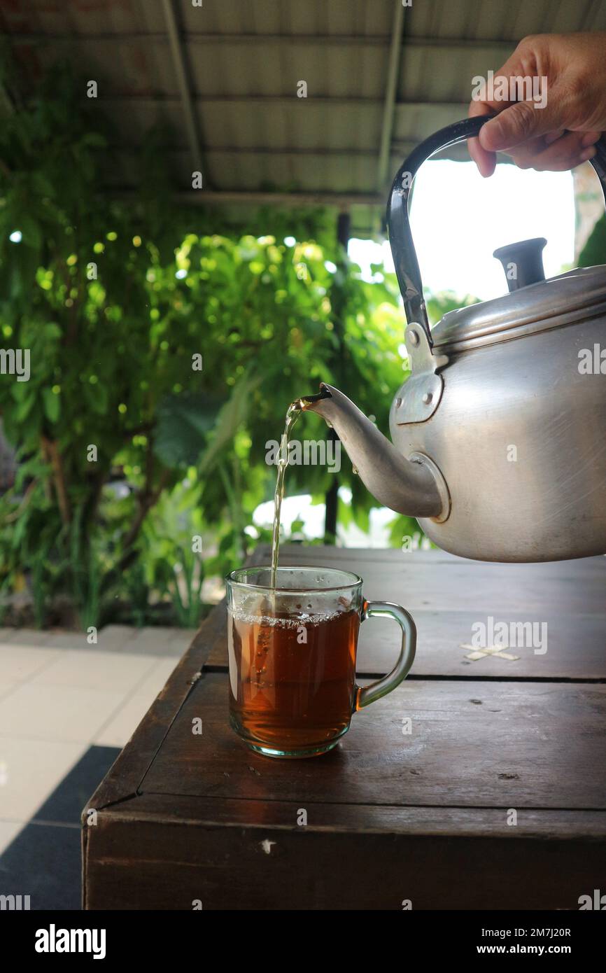 pouring tea from the teapot into glasses Stock Photo - Alamy