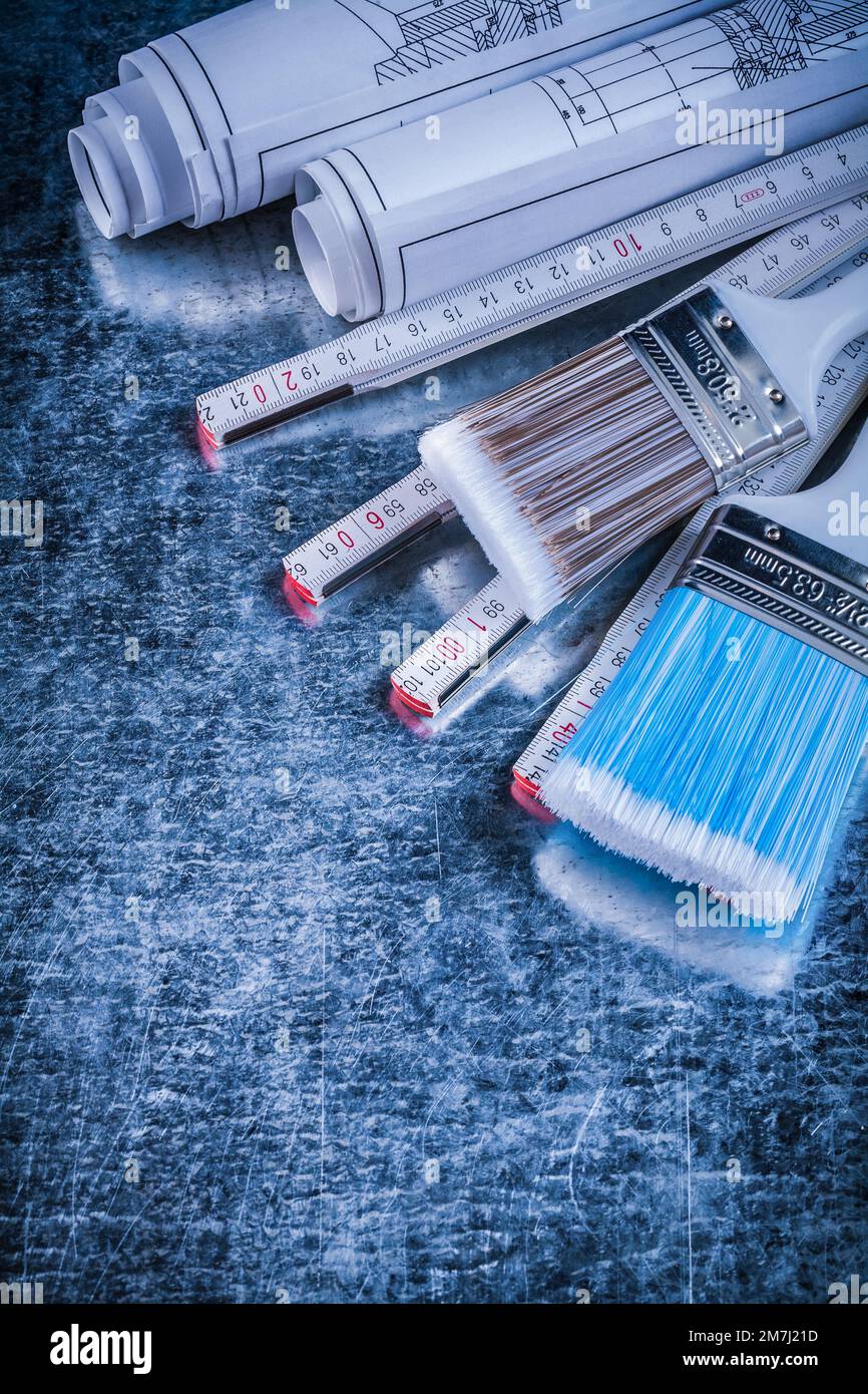 Wooden meter paint brushes rolled up blueprints construction concept ...