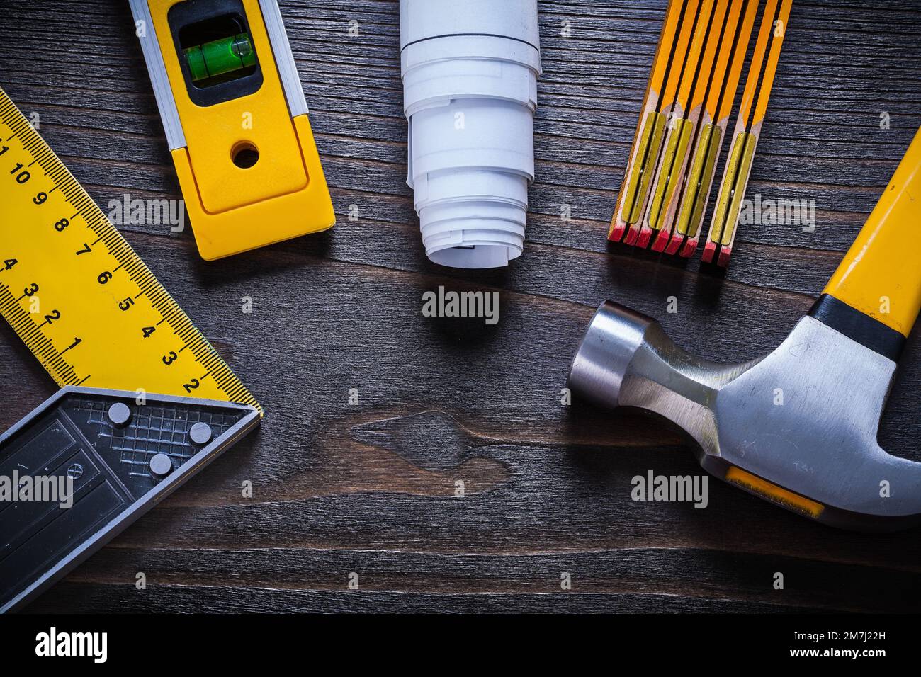 Yellow construction level try square rolled up white blueprint wooden ...