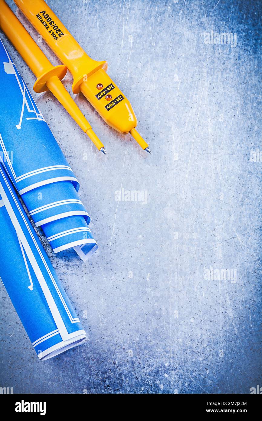 Yellow electrical tester blue rolled construction drawings on metallic ...