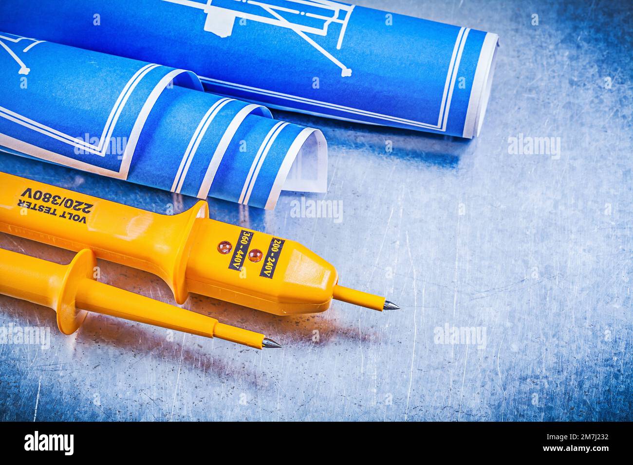Yellow electrical tester blue engineering drawings on metallic ...