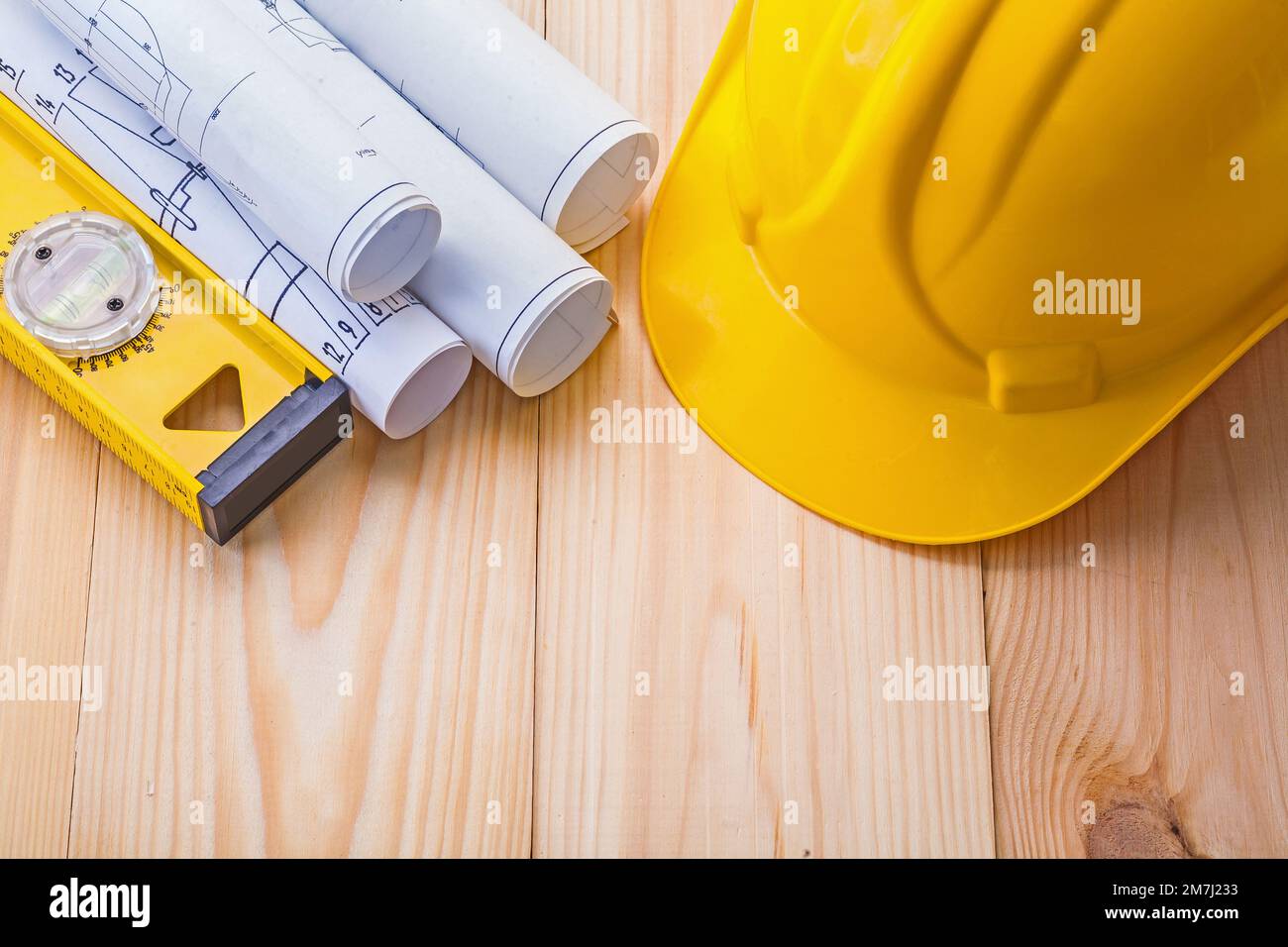 yello helmet rolled up white blueprints level on wooden boards ...
