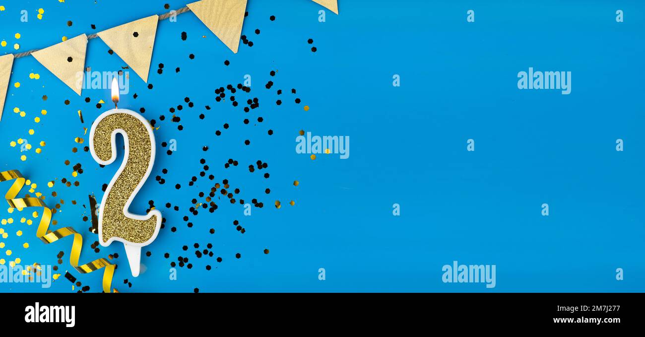 Number 2 gold celebration candle on star and glitter blue background ...