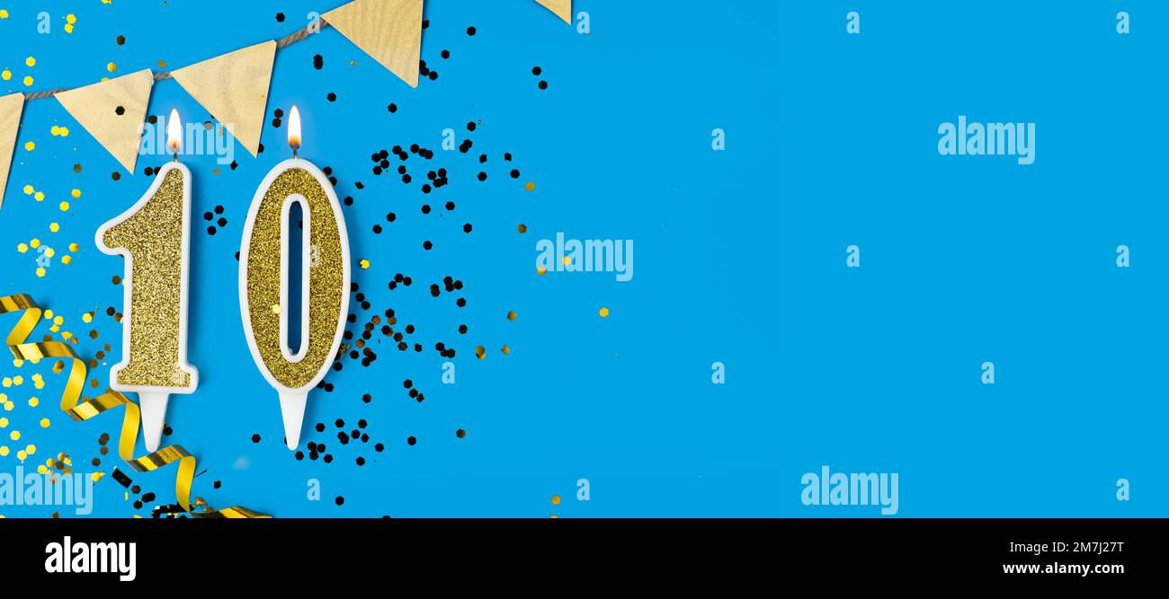 Number 10 gold celebration candle on star and glitter blue background ...