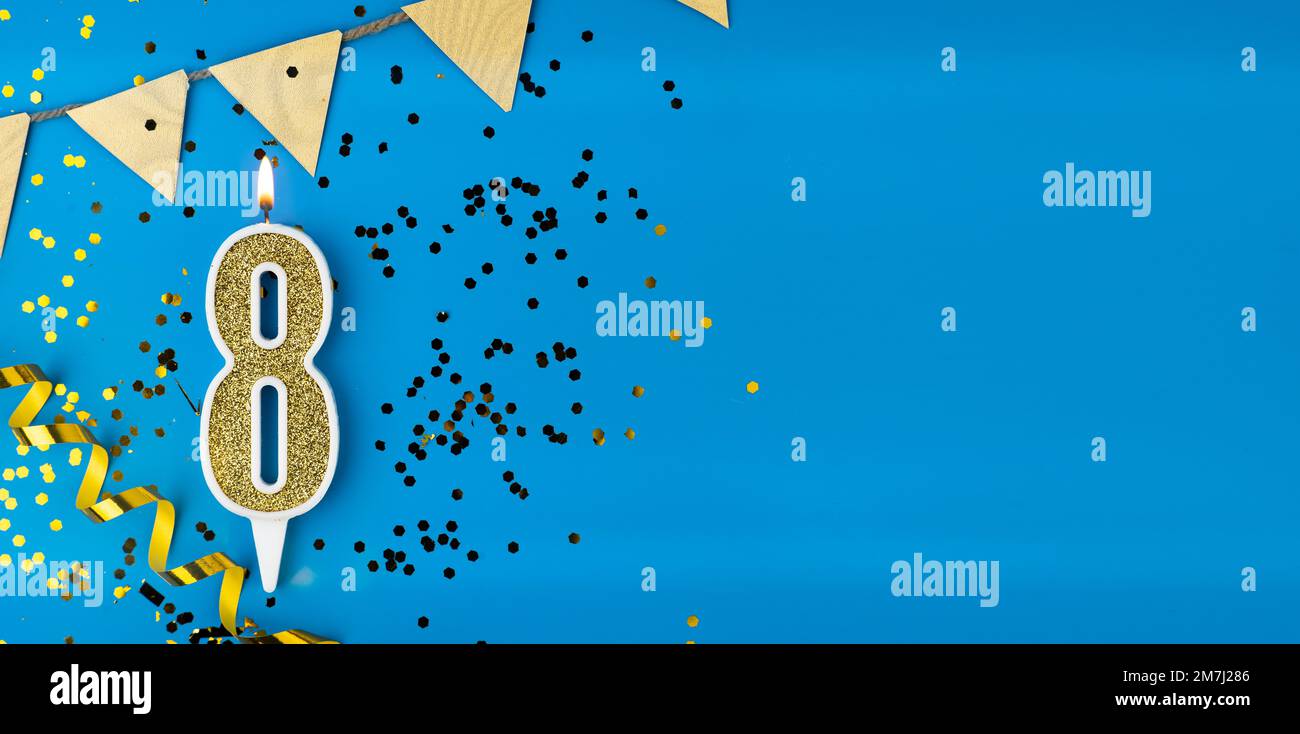 Number 8 gold celebration candle on star and glitter blue background ...