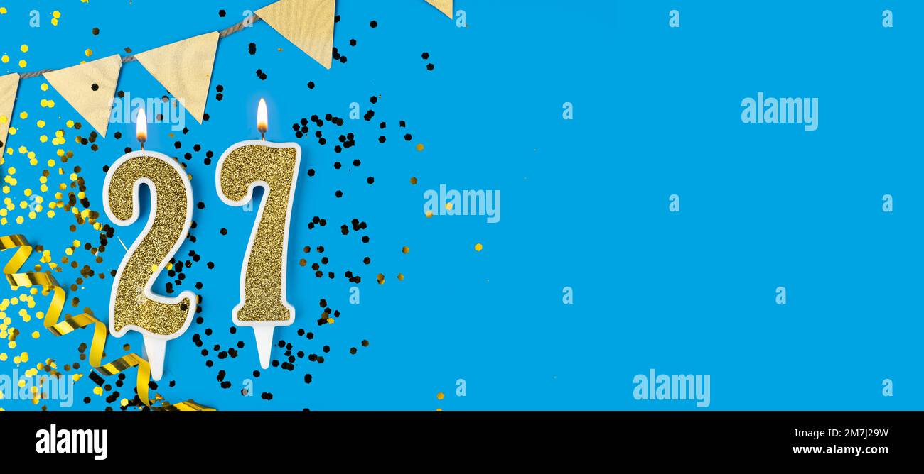 Number 27 gold celebration candle on star and glitter blue background ...