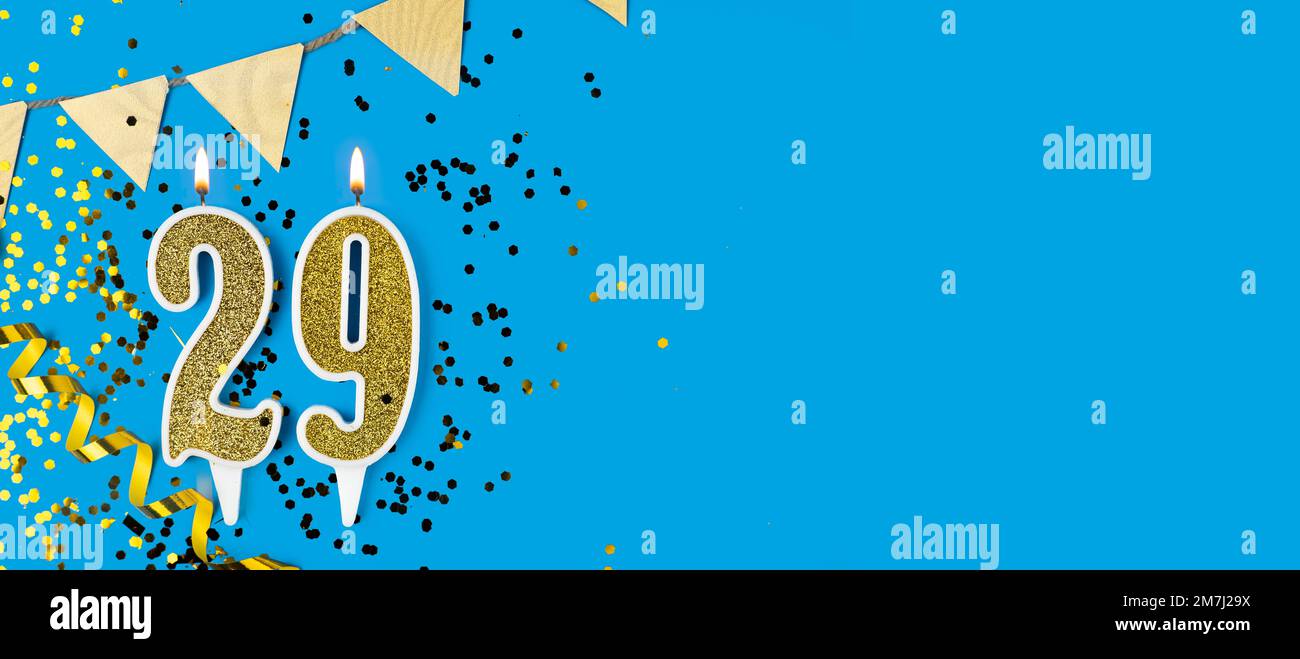 Number 29 gold celebration candle on star and glitter blue background ...