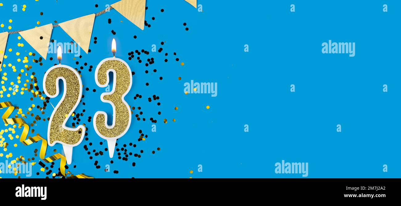Number 23 gold celebration candle on star and glitter blue background ...