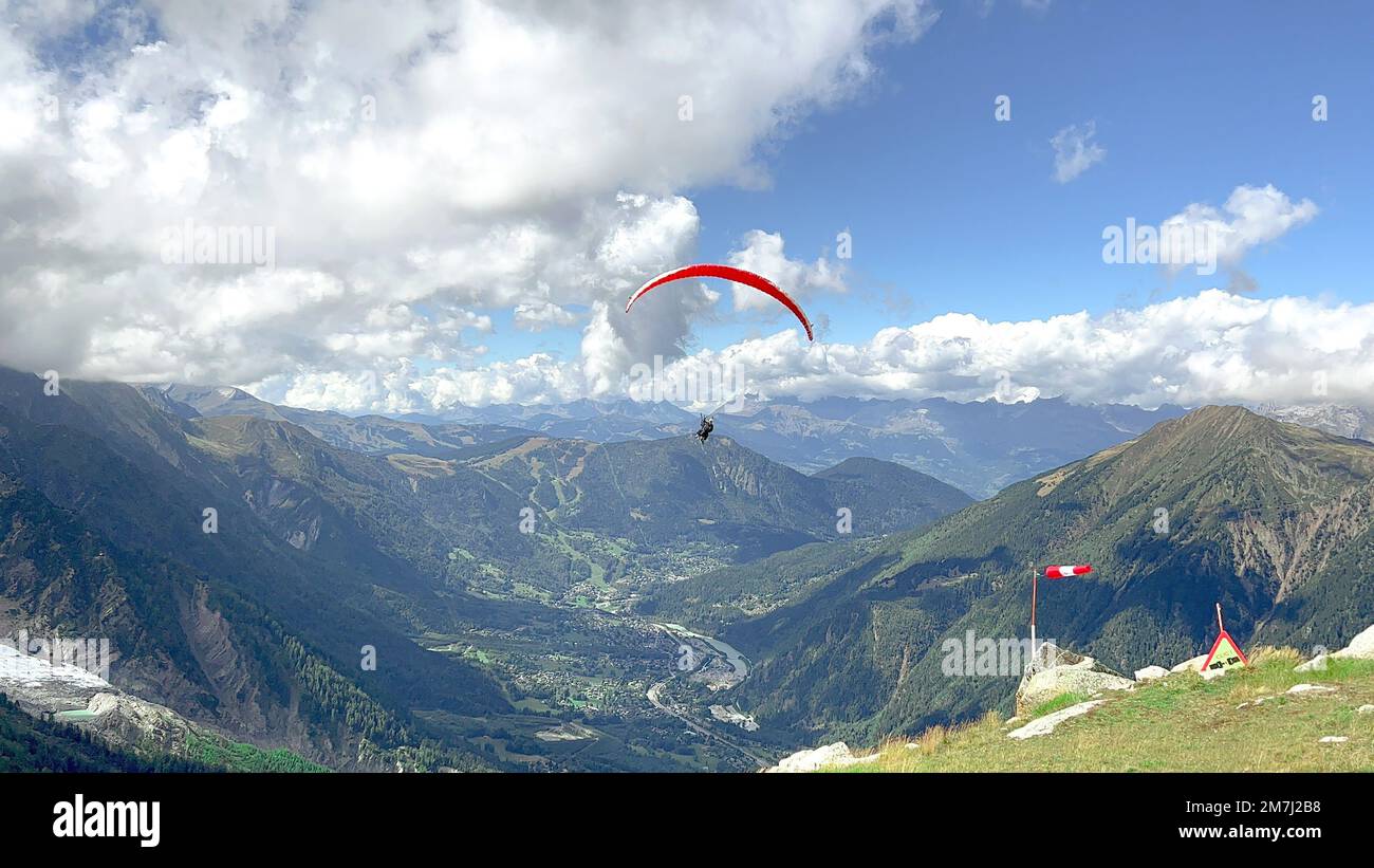 An aerial view of a paraglider flying above lush green mountain range ...