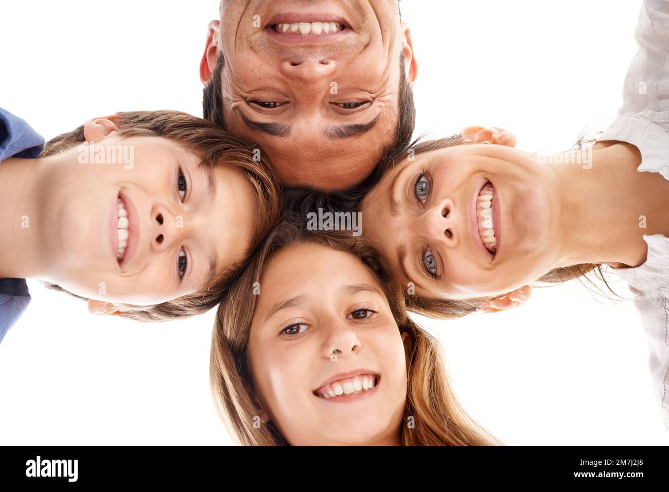 Family huddle. Low-angle shot of a happy family of four standing in a ... Family huddle. Low-angle shot of a happy family of four standing in a ...