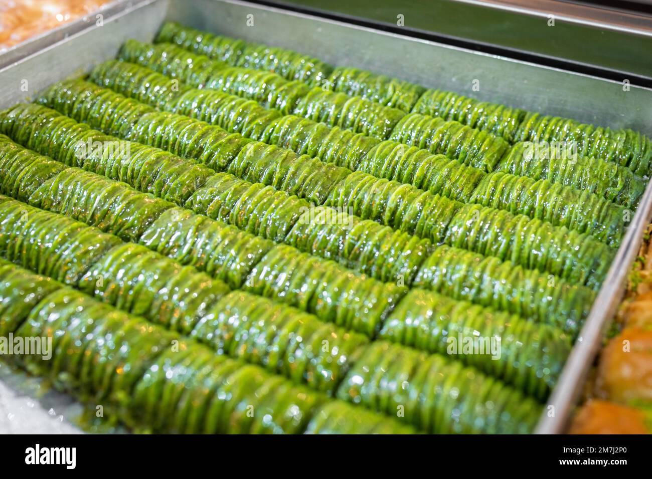 Close-up of green pistachio baklava on the counter among other types of ...