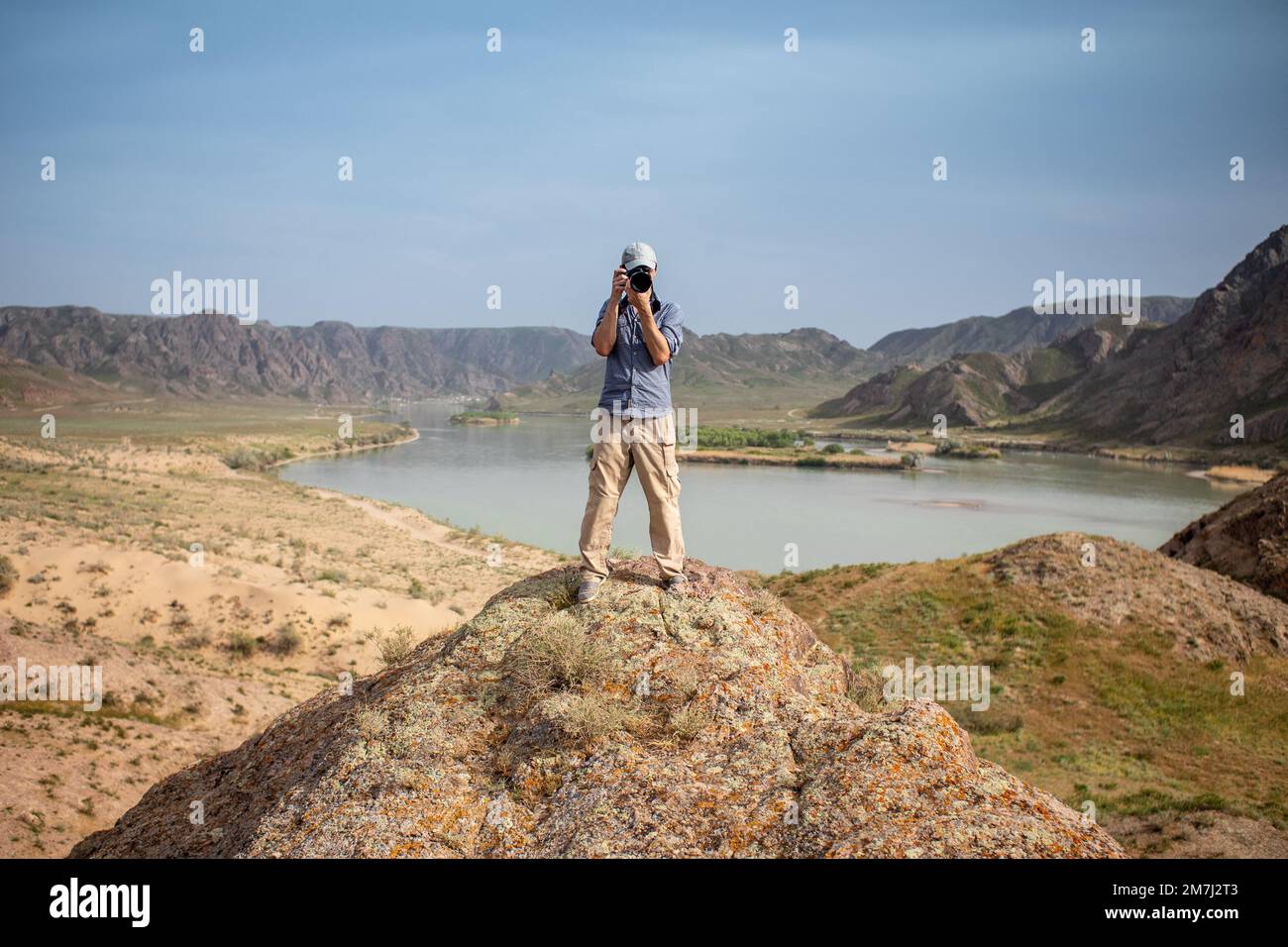 Professional photographer takes photos with camera in hands on rocky ...