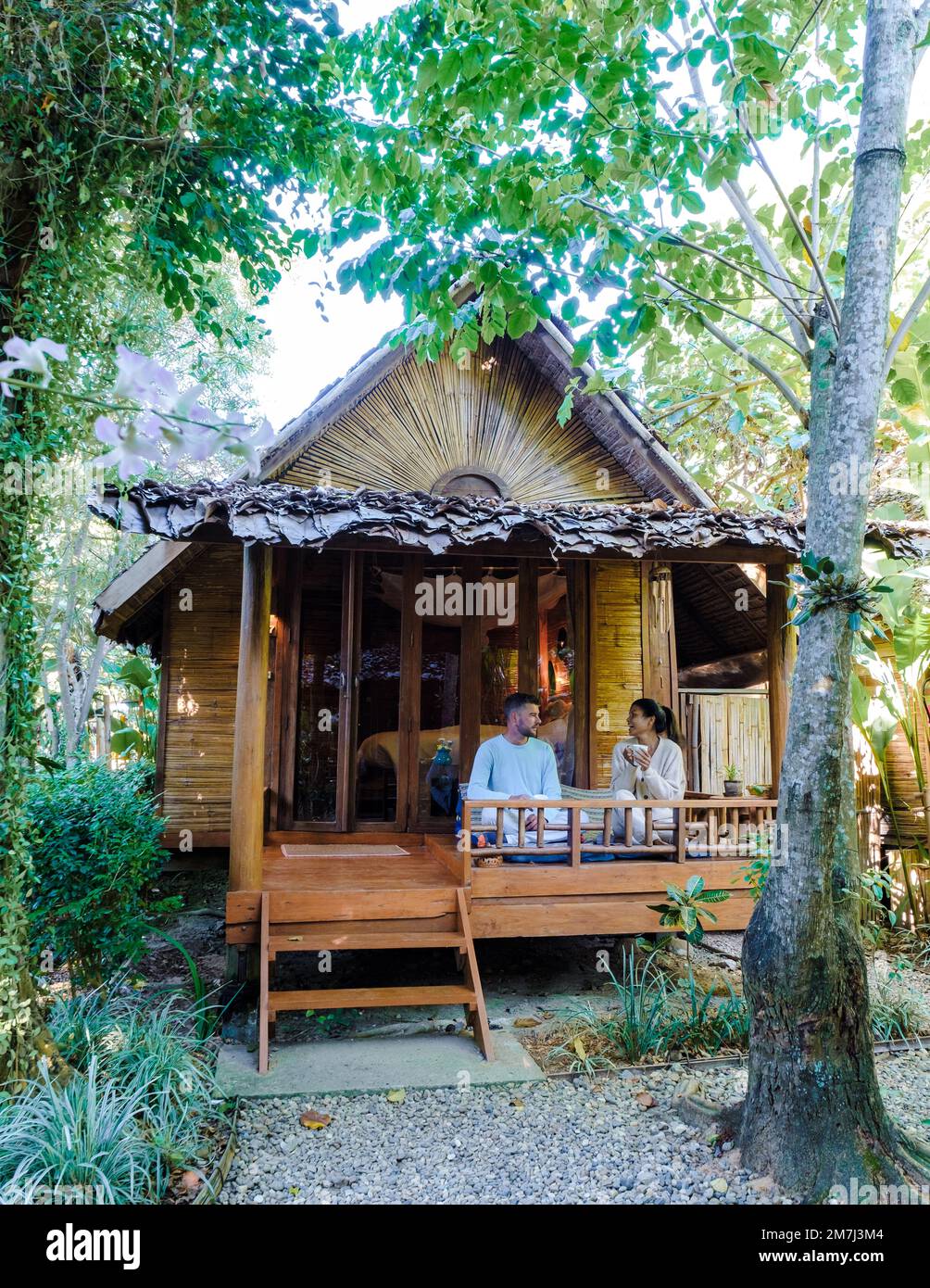 A couple of men and women at a bamboo hut homestay in Northern Thailand ...