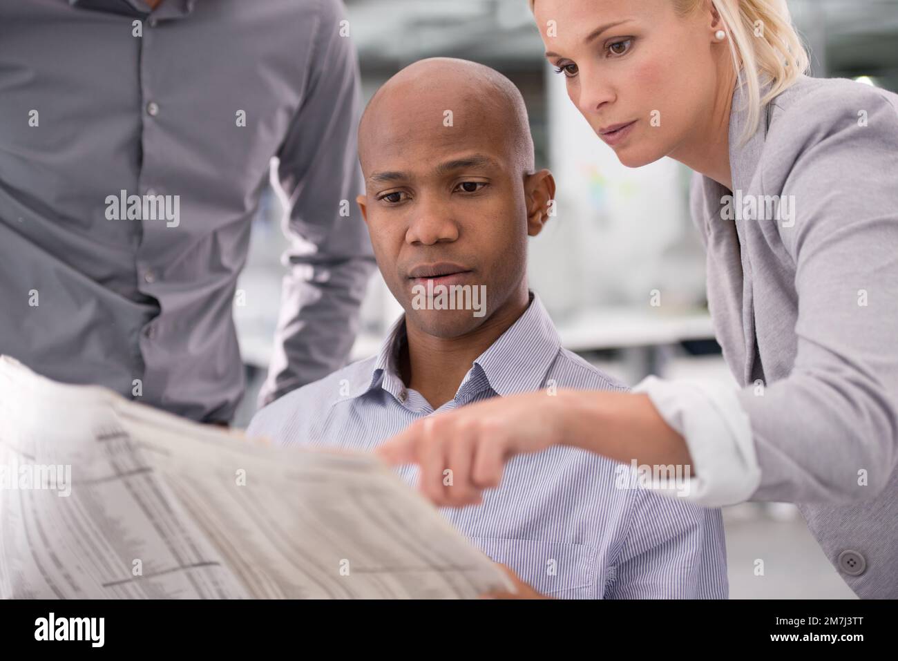 Discussing the dailies. a group of work colleagues reading a newspaper ...