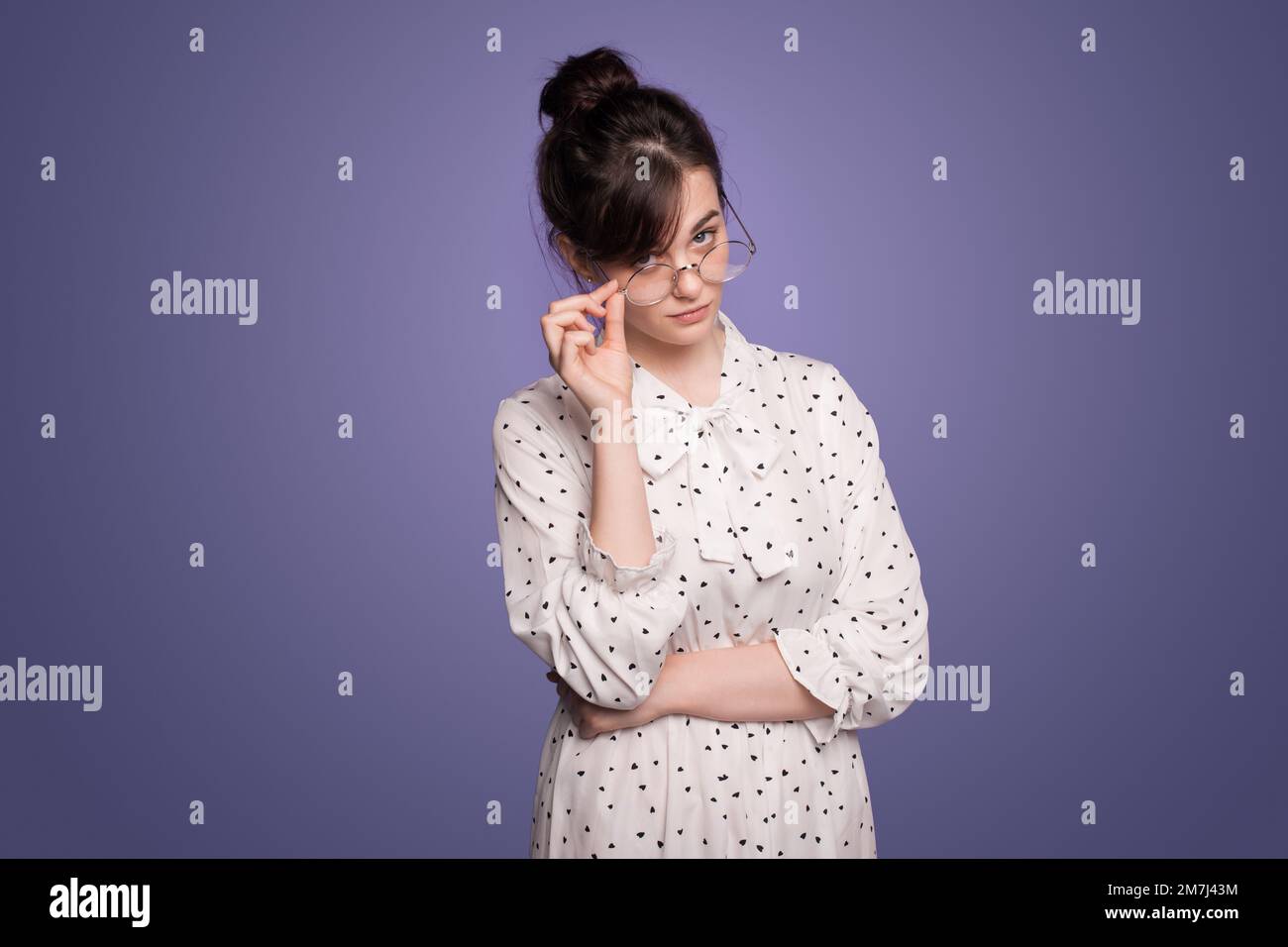 Portrait of serious suspicious young woman in eyeglasses looking at ...