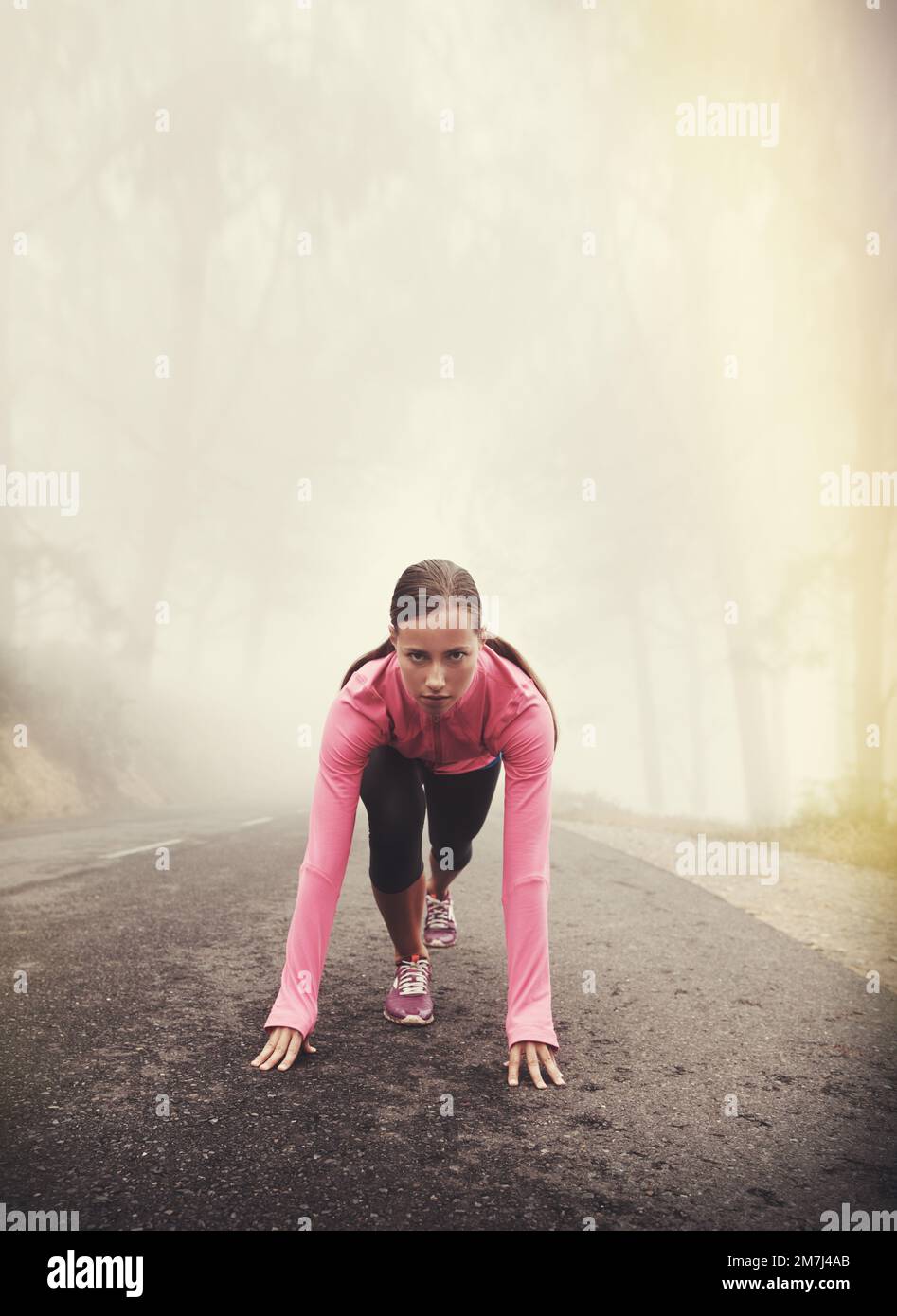 Ready for anything. a young female runner about to start a training ...