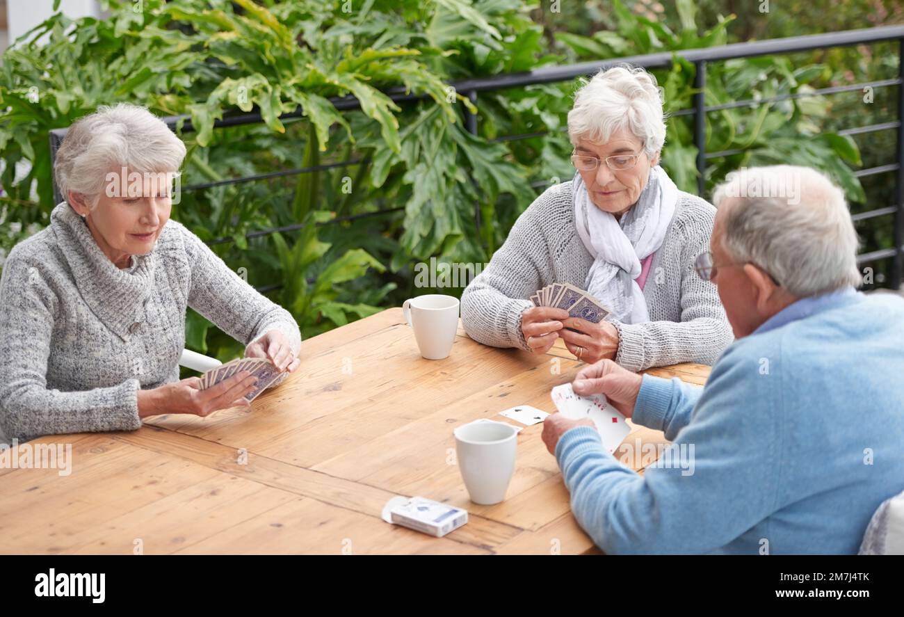 Poker is meant to be enjoyed. A group of seniors playing cards together ...