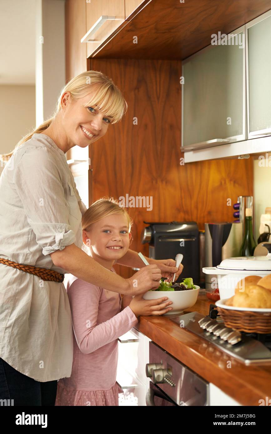 Mommys little helper. a cute girl and her mother cooking in the kitchen ...
