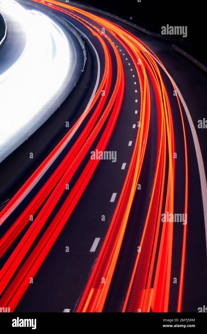 A vertical aerial view of light trails of cars on a highway road at ...