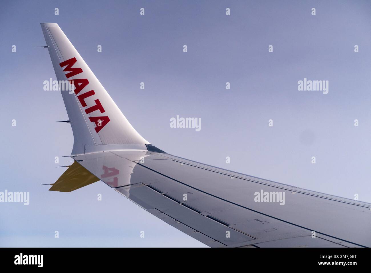 The view of a wing of a Malta Airline plane flying in a blue sky Stock ...