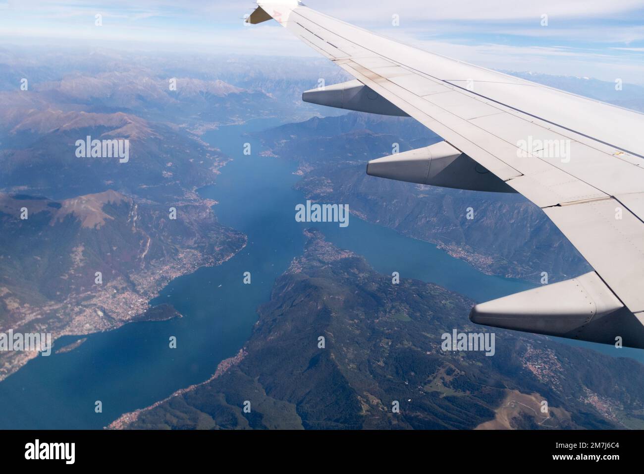 The view of a wing of a plane flying in a blue sky over a lake Stock ...
