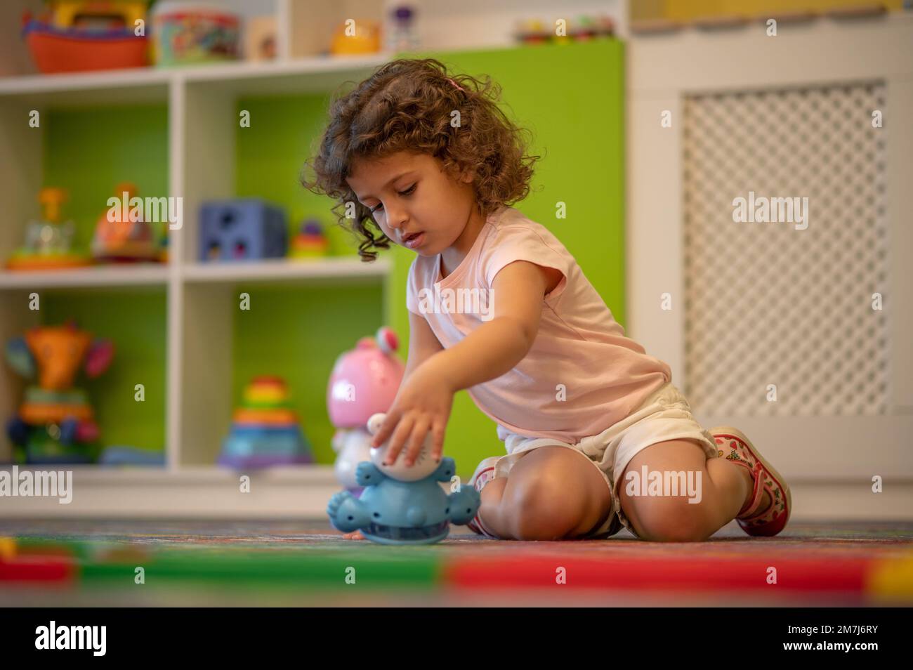 Cute little girl playing in a play room and looking interested Stock ...