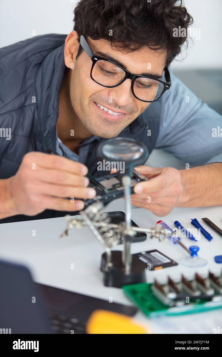 engineer soldering microcircuit though magnifier Stock Photo - Alamy