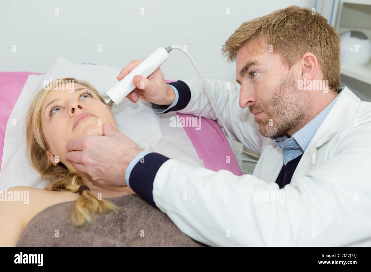doctor using medical implement on female patients temple Stock Photo ...