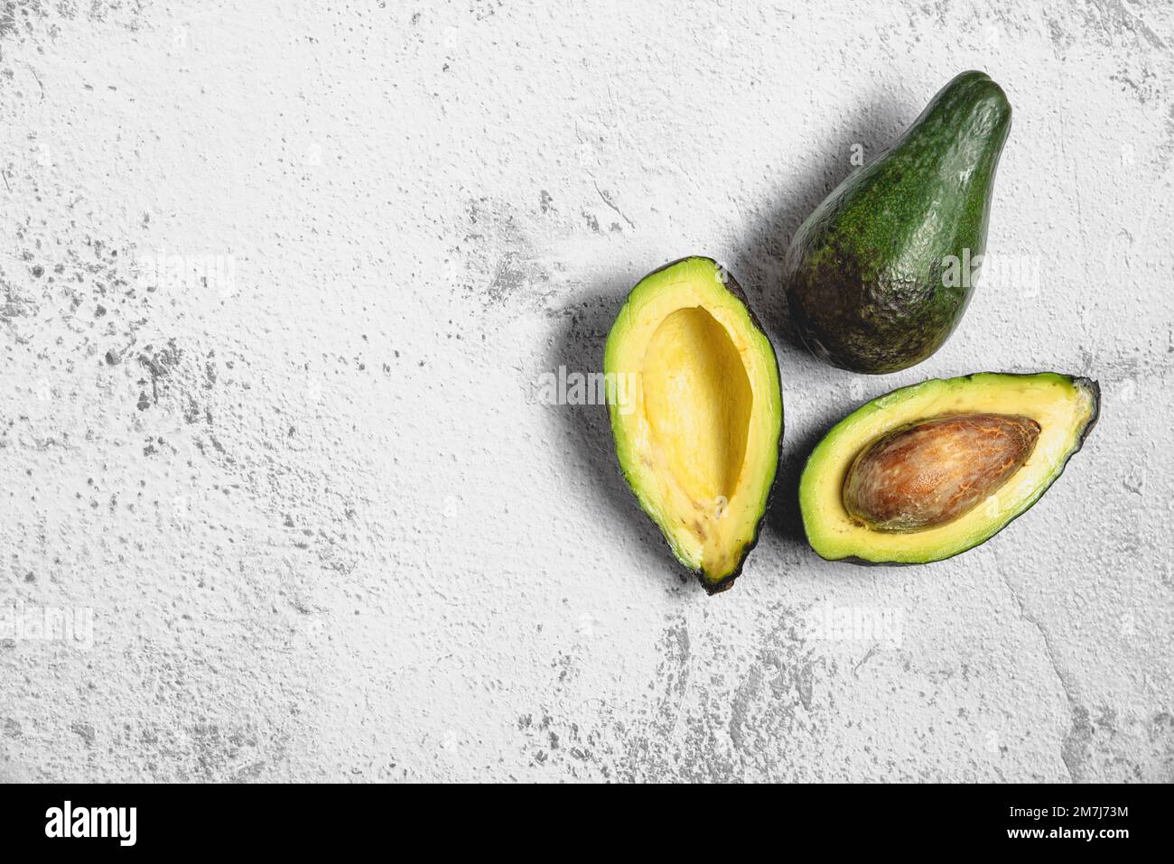 Top view of both cut and whole ripe avocado on white stone table Stock ...