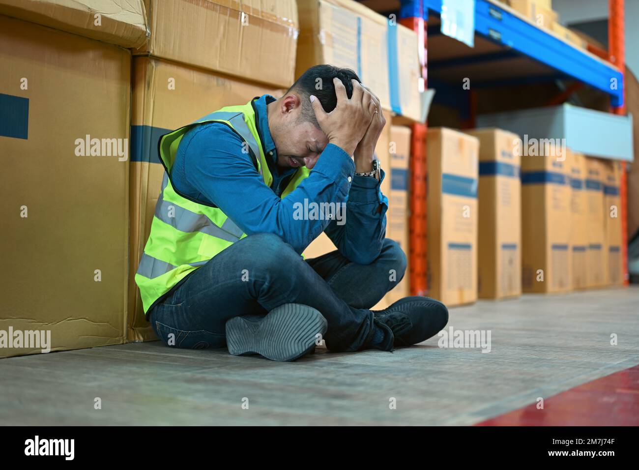 Tired warehouse worker taking break from hard work, sitting between ...