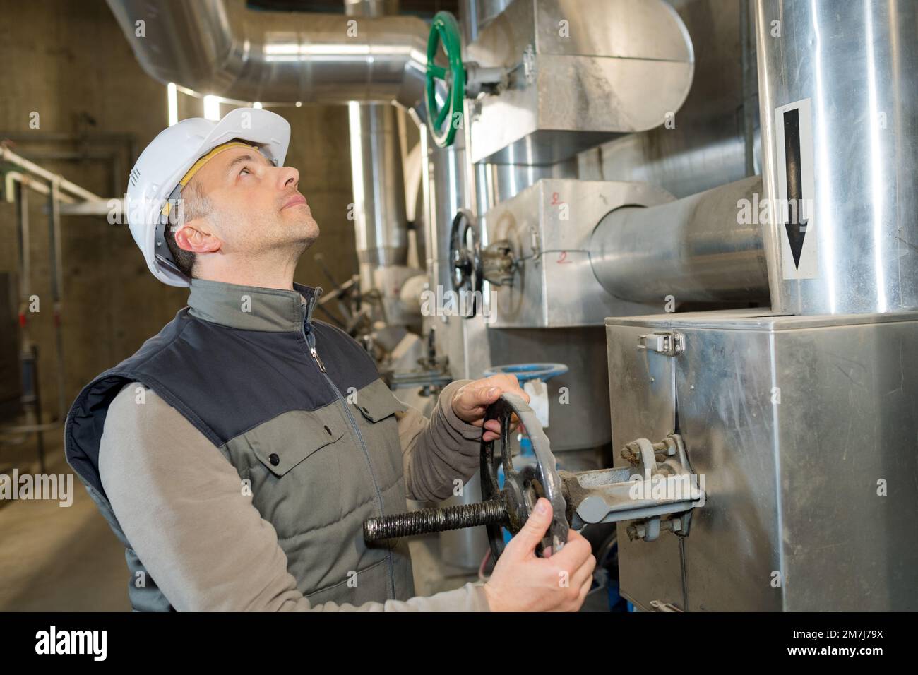 man turning wheel on industrial machinery Stock Photo - Alamy