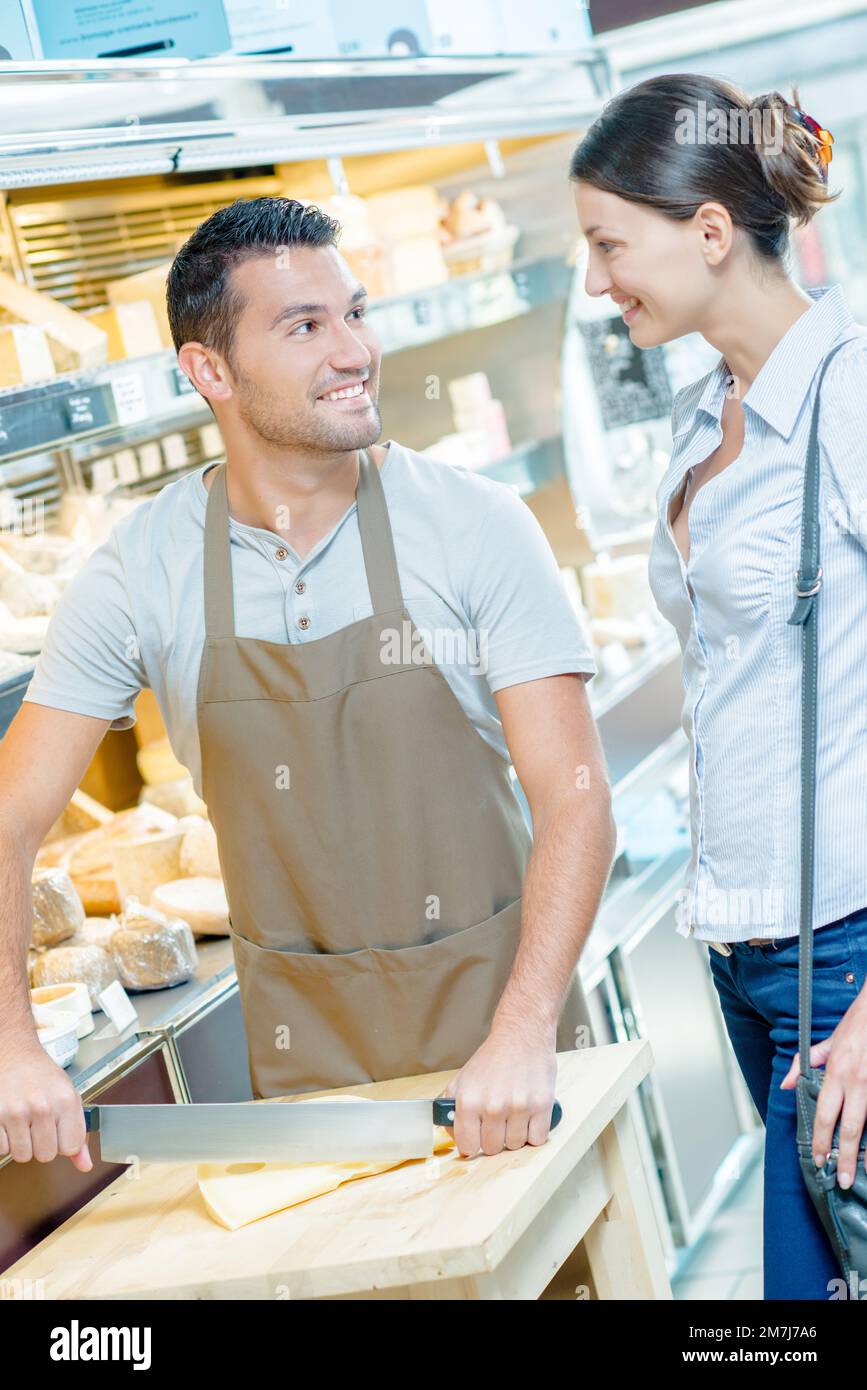 Man cutting cheese for customer with two-handled knife Stock Photo - Alamy