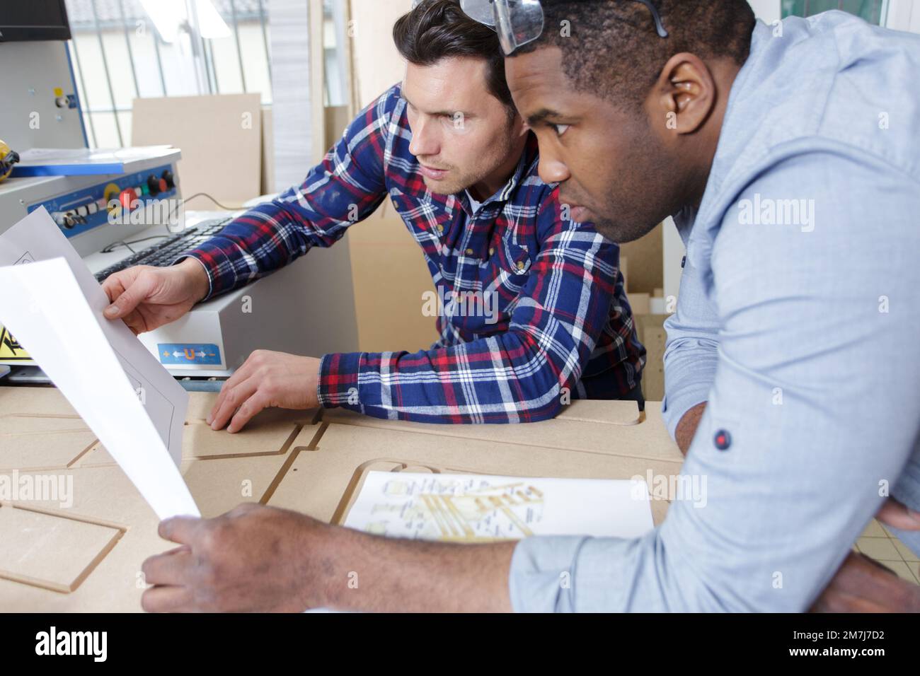 two male colleagues in factory looking at paperwork Stock Photo - Alamy