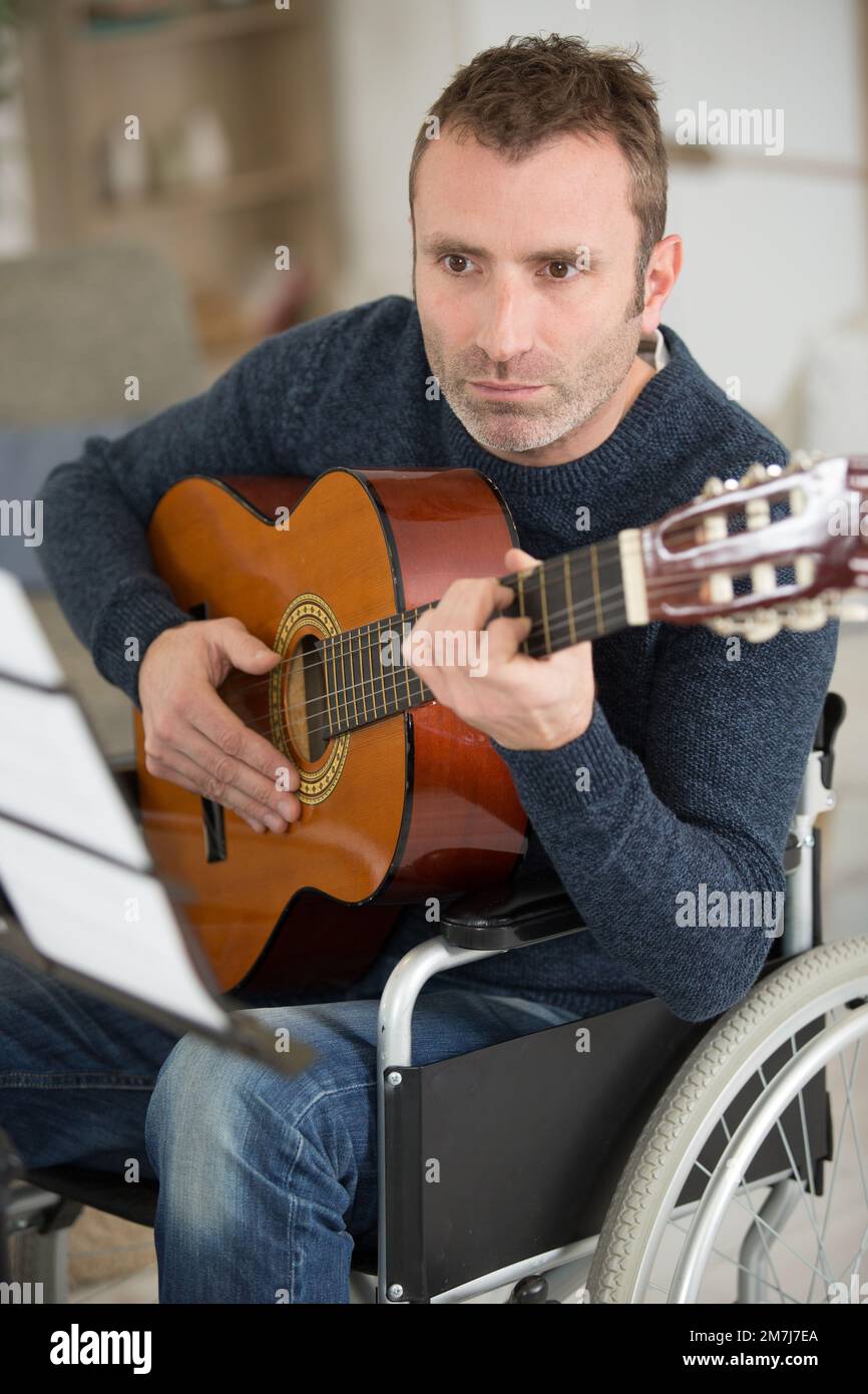 musician in wheelchair playing guitar at home Stock Photo - Alamy