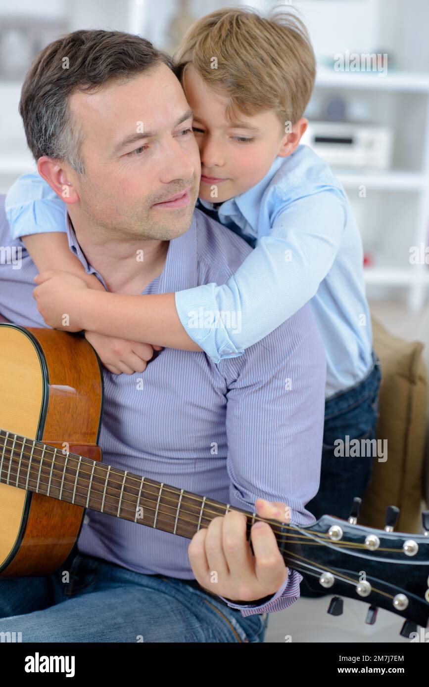 Child hugging man playing guitar Stock Photo - Alamy