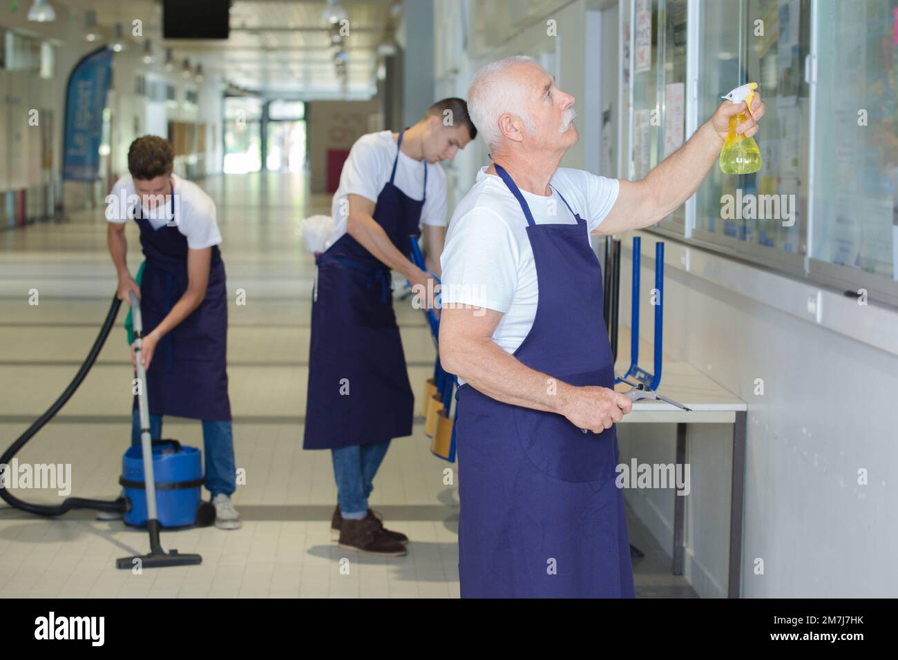 male cleaning team working in large lobby area Stock Photo - Alamy