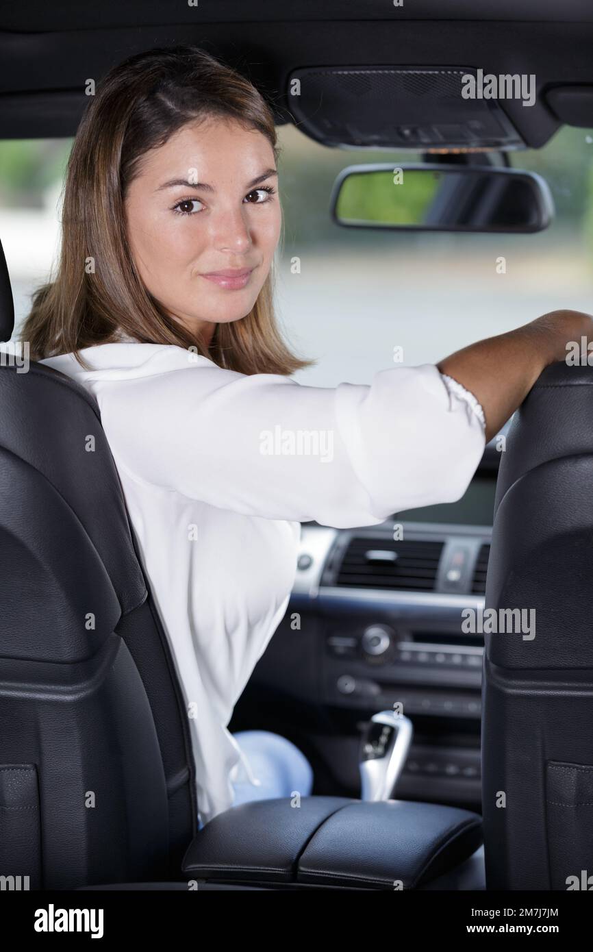 female driver turning to look into back of car Stock Photo - Alamy