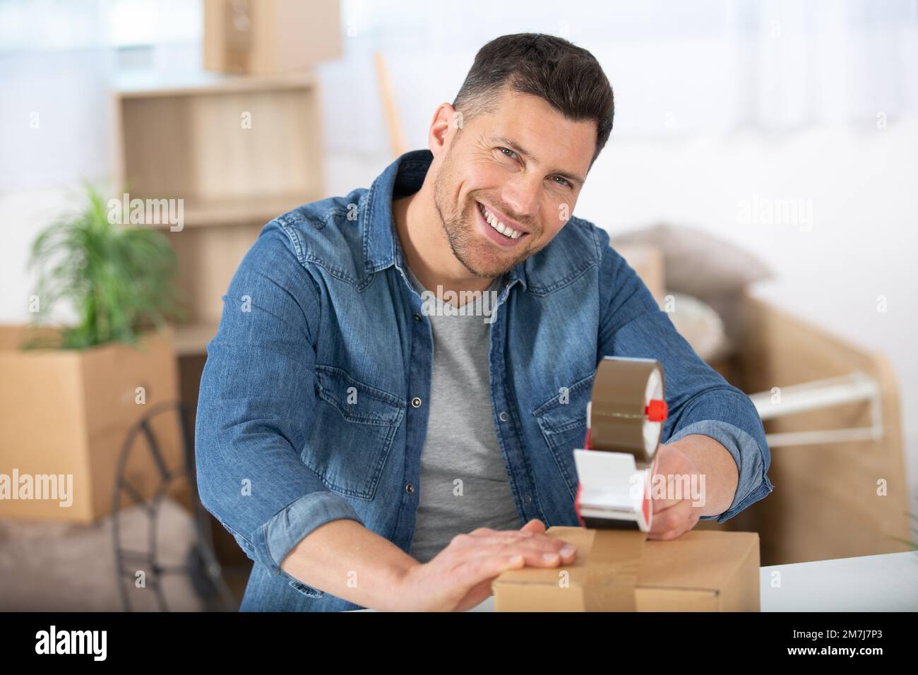 happy man closing boxes with duct tape Stock Photo - Alamy